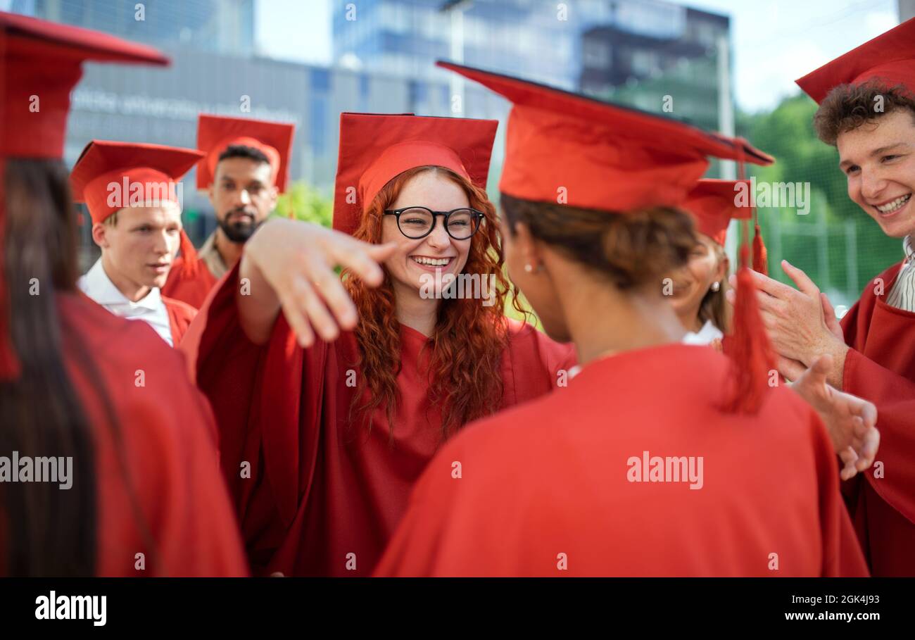 Cheerful university students friends celebrating and hugging outdoors ...