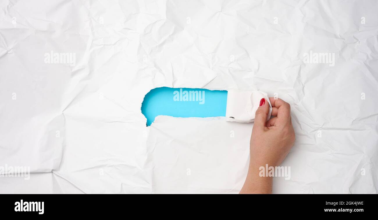 female hand tears off a strip from white crumpled paper, place for an ...