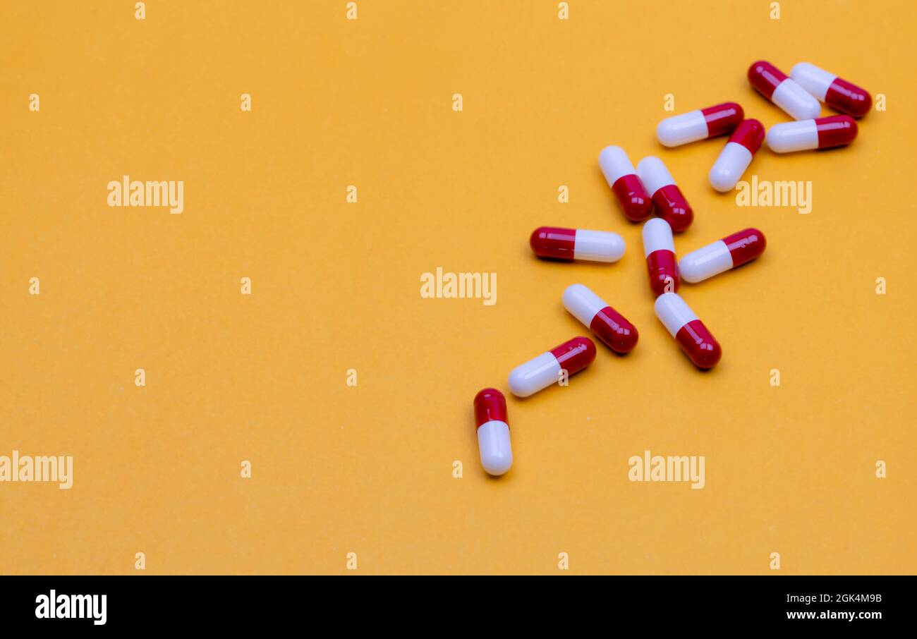Top view of red-white capsule pills on yellow background. Pharmacy web ...
