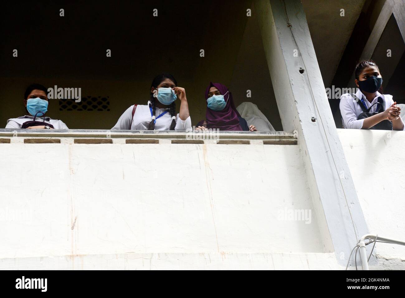 Students wearing face masks look out from the balconies of the school ...