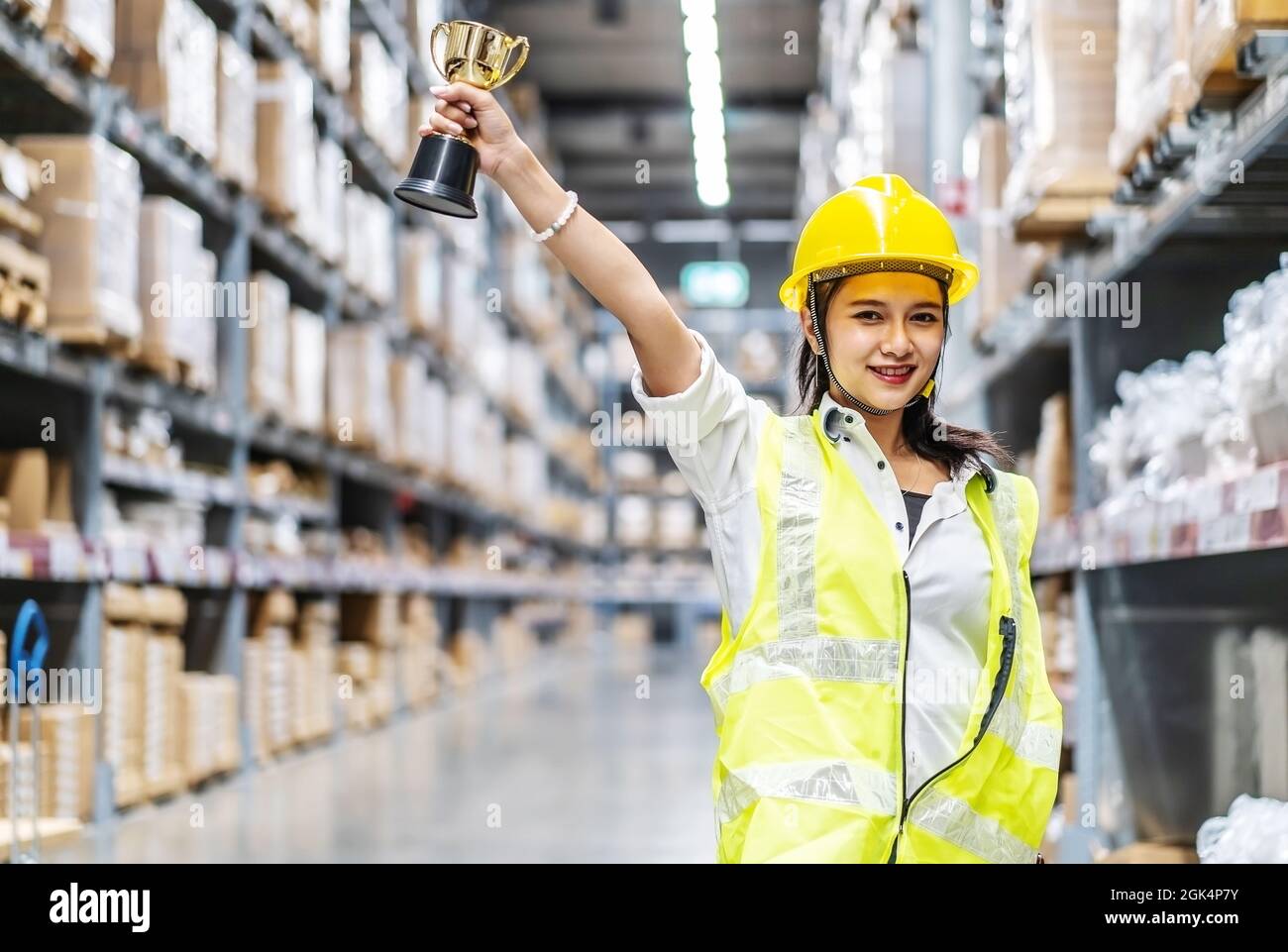 Happy woman warehouse worker holding a trophy after being selected as ...