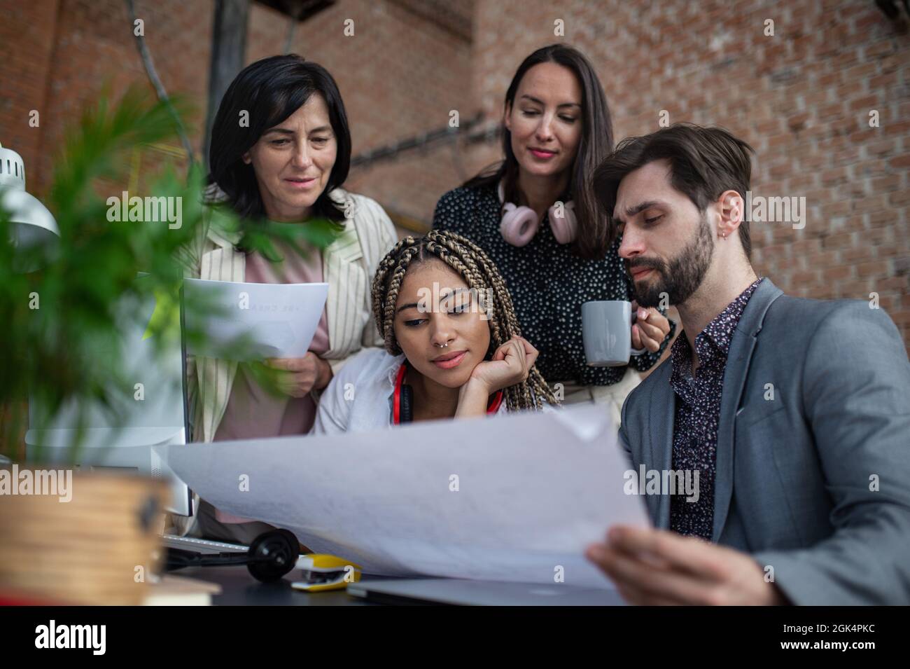 Young and old businesspeople sitting and working at desk in office ...