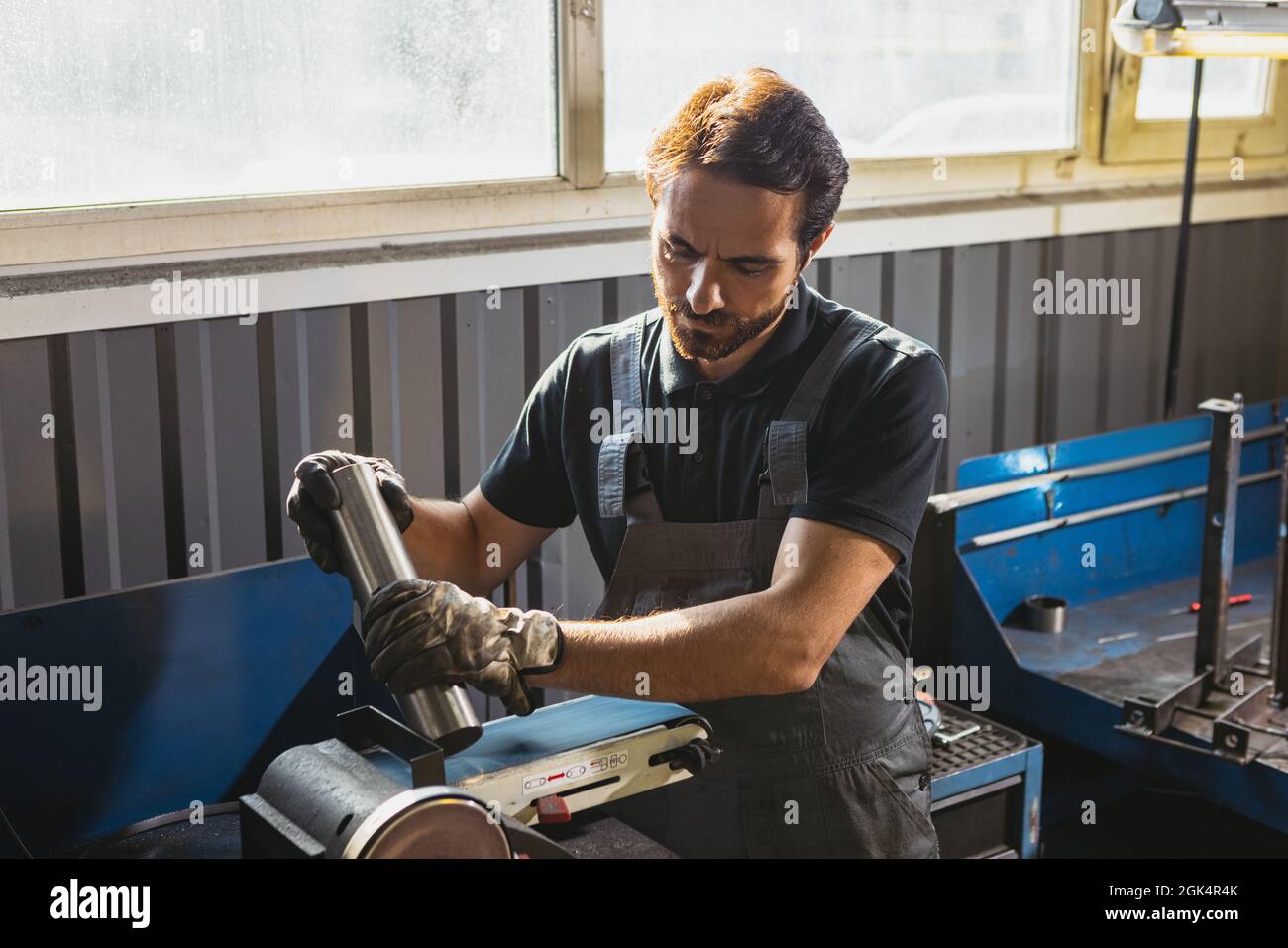 Portrait of young man, male auto mechanic in dungarees working at car ...