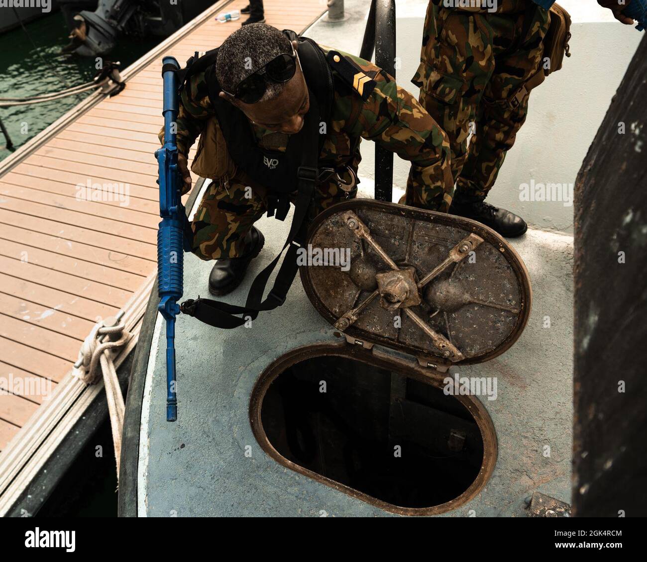 A Comorian Sailor searches a vessel’s hatch while conducting visit ...