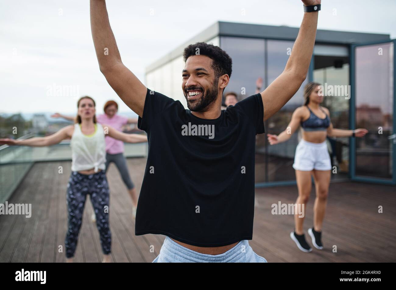 Group of young people doing exercise outdoors on terrace, sport and ...