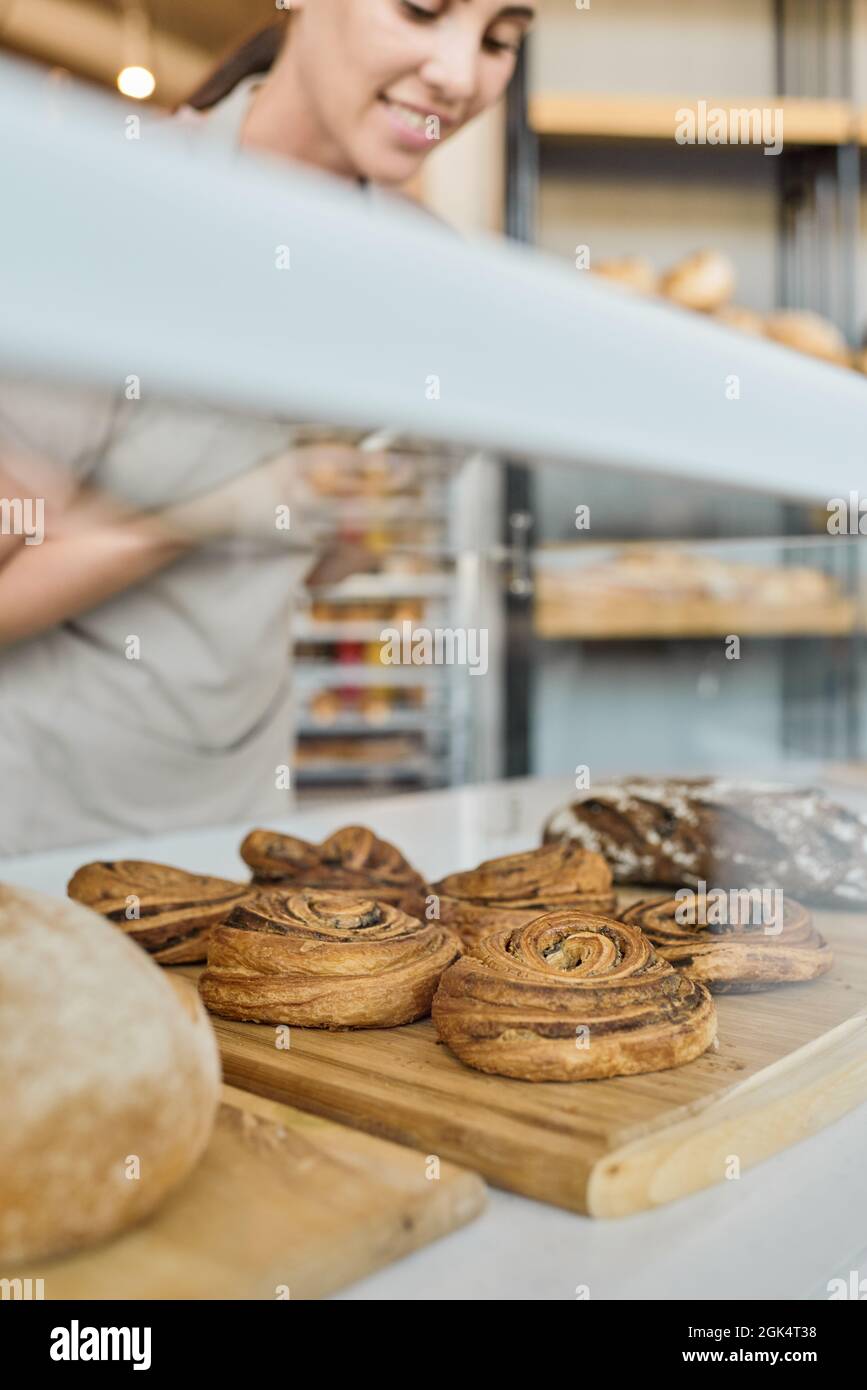 Close-up of woman in apron putting buns on display in bakery shop Stock ...