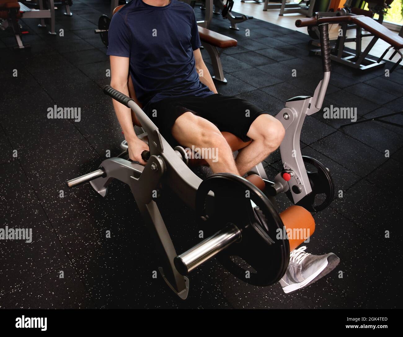 Sporty young man training legs in gym Stock Photo - Alamy