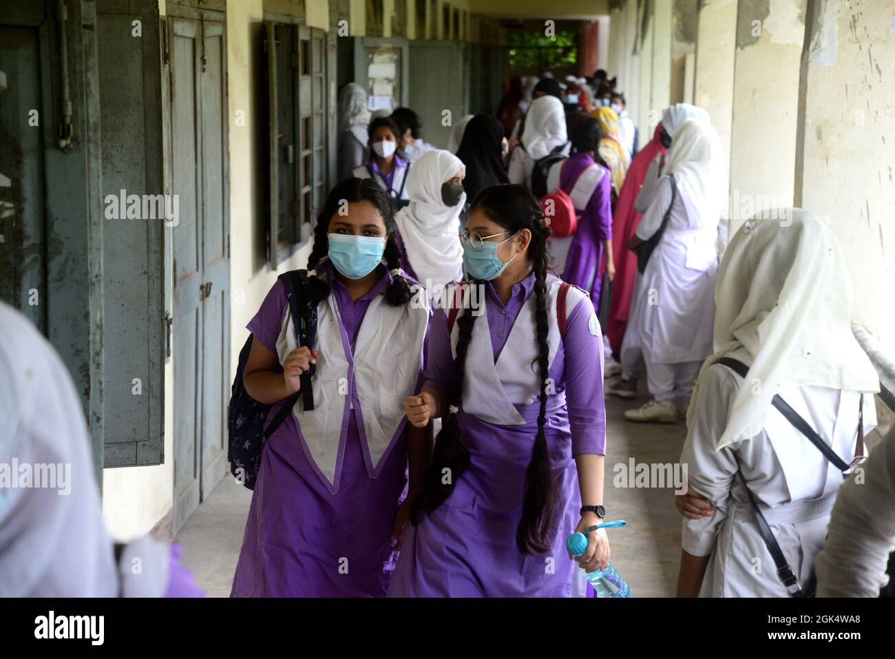 Students wearing face masks look out from the balconies of the school ...