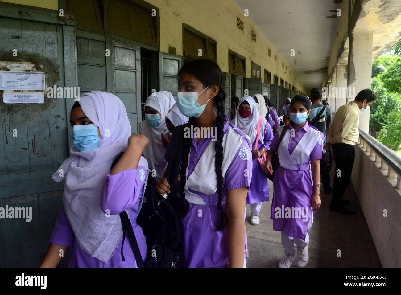Students wearing face masks look out from the balconies of the school ...