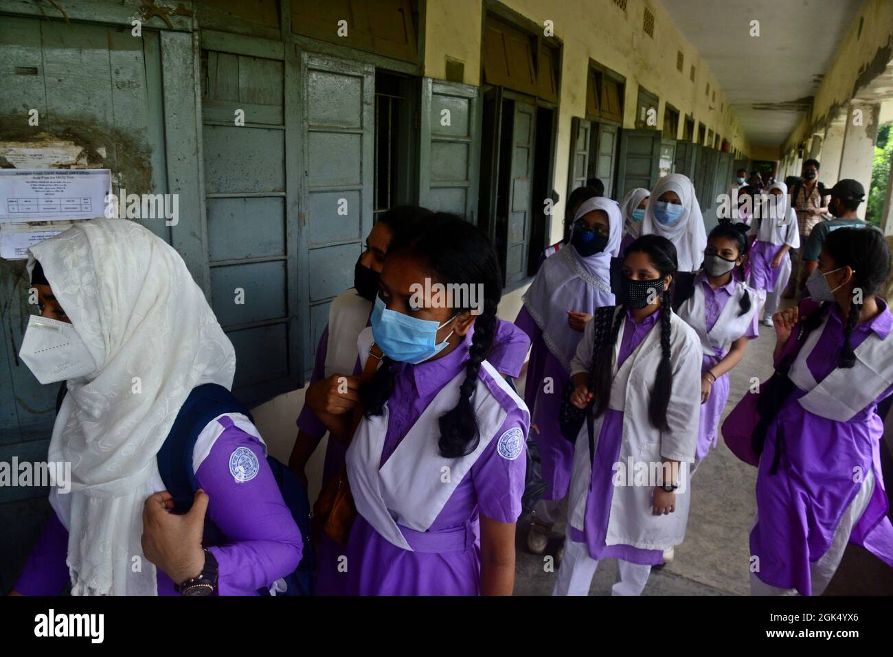 Students wearing face masks look out from the balconies of the school ...