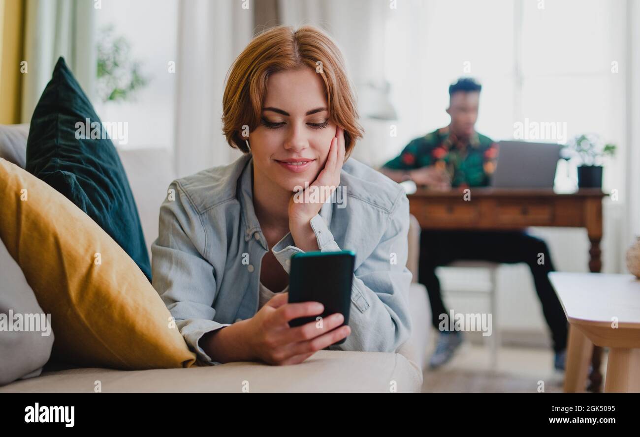 Young couple at home using digital divices, smartphone and laptop ...