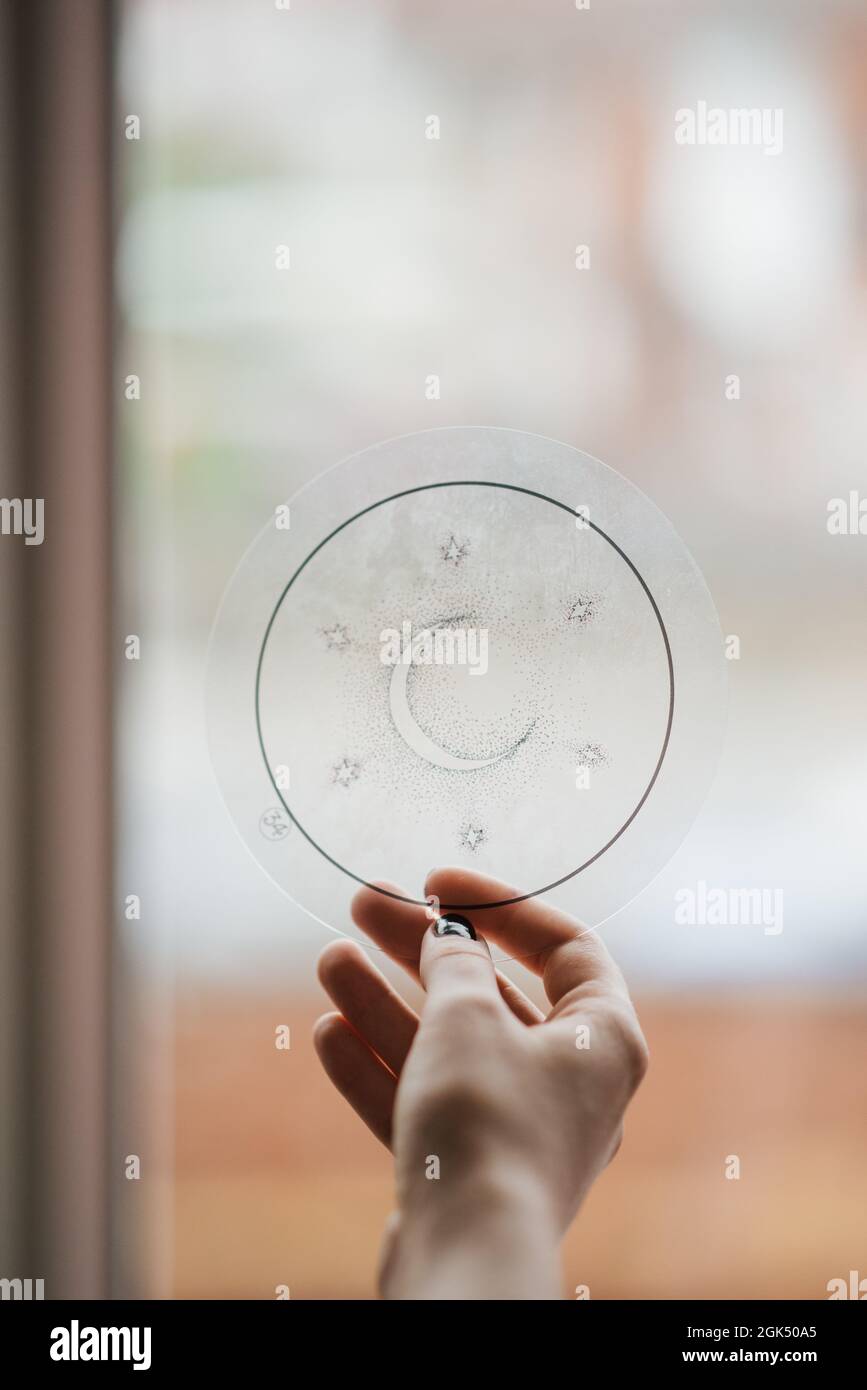 Vertical shot of Caucasian female hand holding a round transparent ...