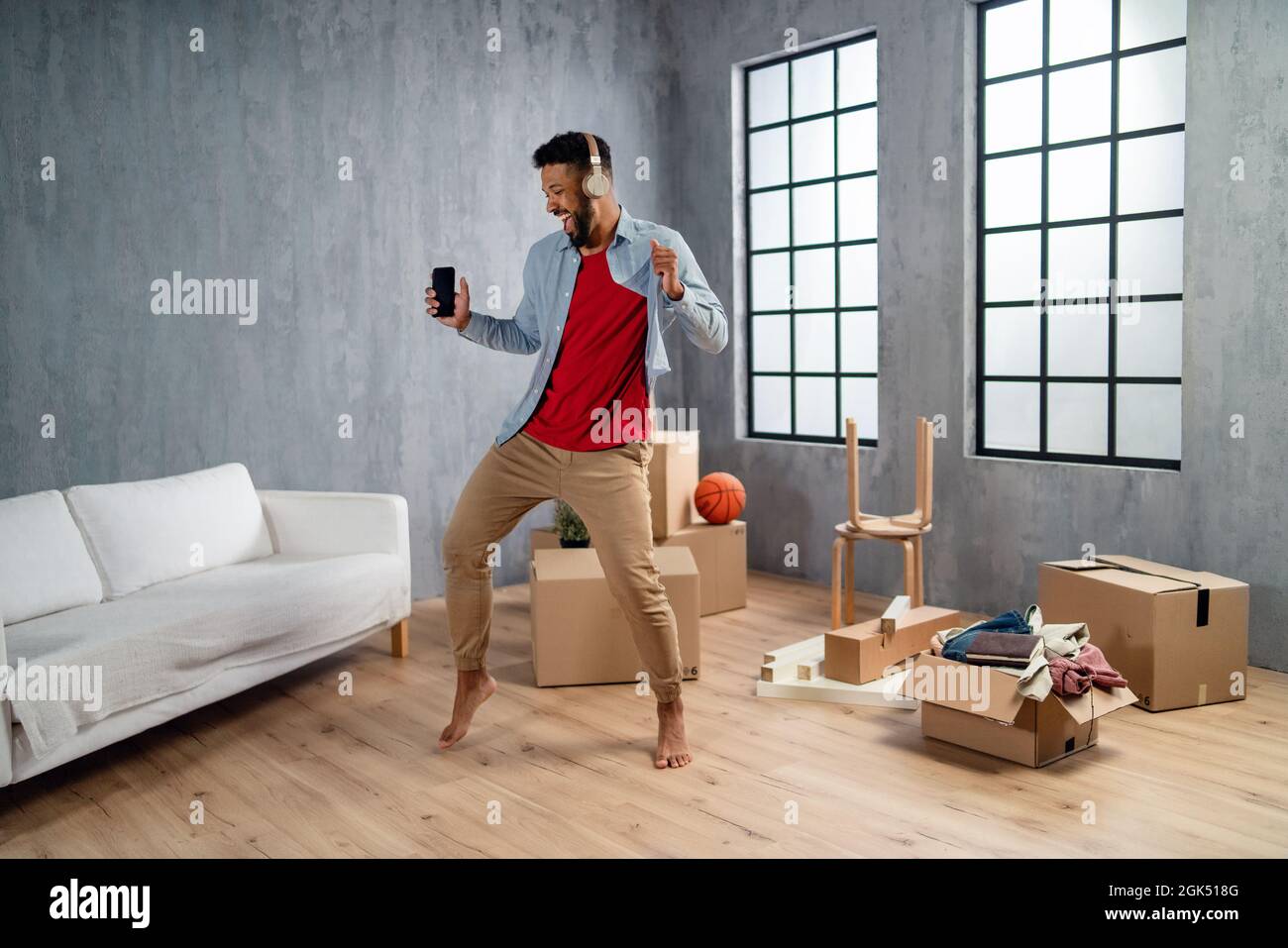 Happy young man with headphones dancing and celebrating moving home ...