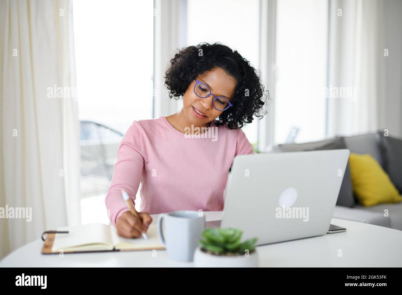 Portrait of happy mature woman working on laptop indoors, home office ...