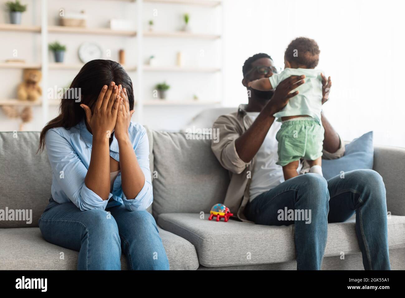 Tired African American mom crying, dad playing with kid Stock Photo - Alamy