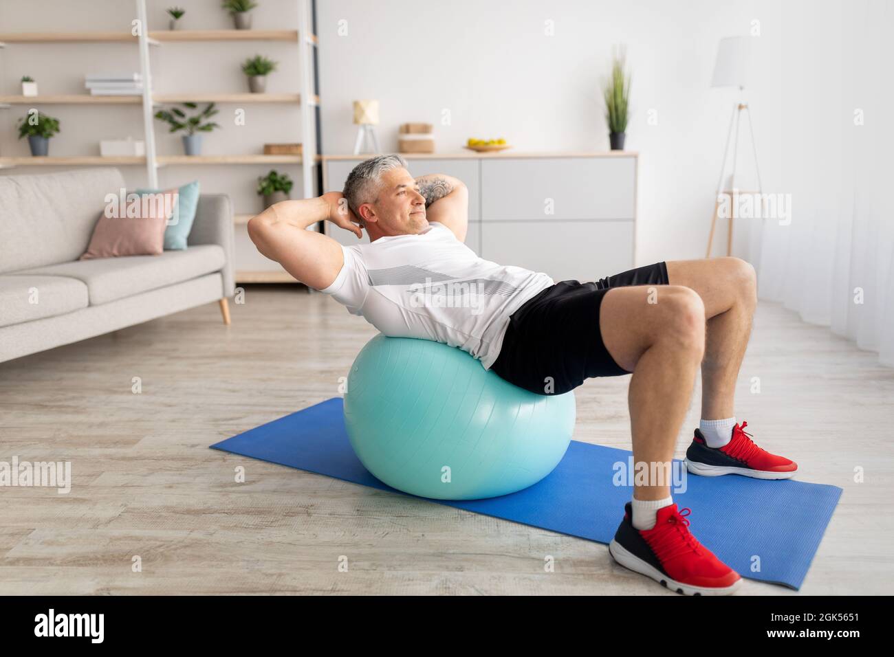 Domestic workout concept. Sporty middle-aged man doing abs exercises at ...