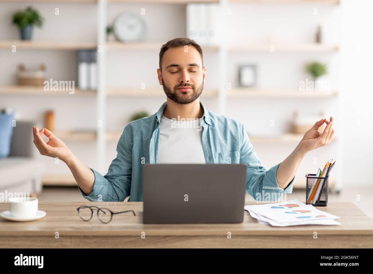 Workplace stress management. Calm Caucasian man meditating with closed ...