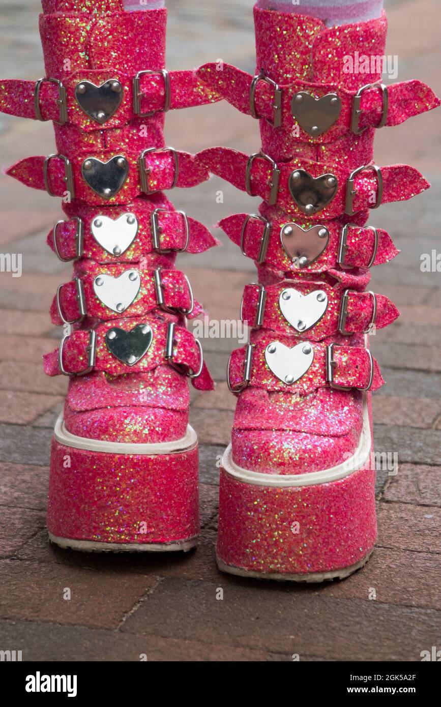 Fashionable pink platform boots with numerous love heart buckles worn ...