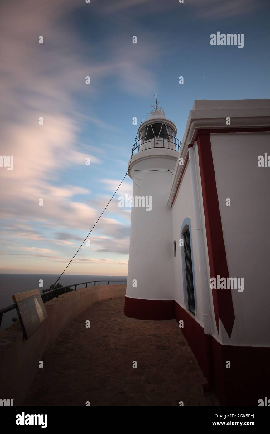Vertical shot of a lighthouse with small building on the seashore with ...