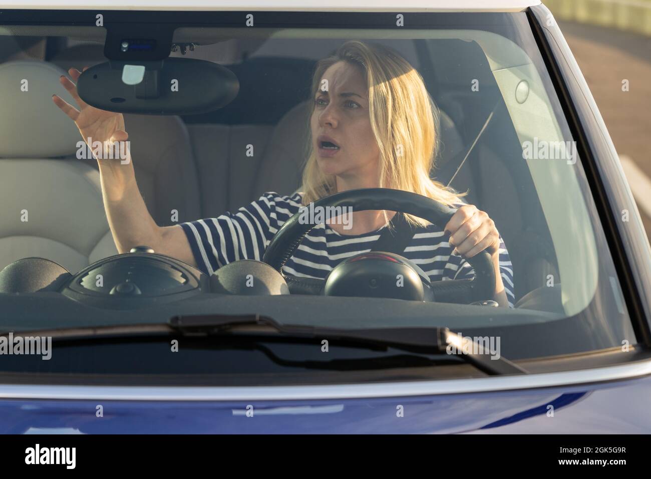 Scared woman driver look in back view mirror at small accident car ...