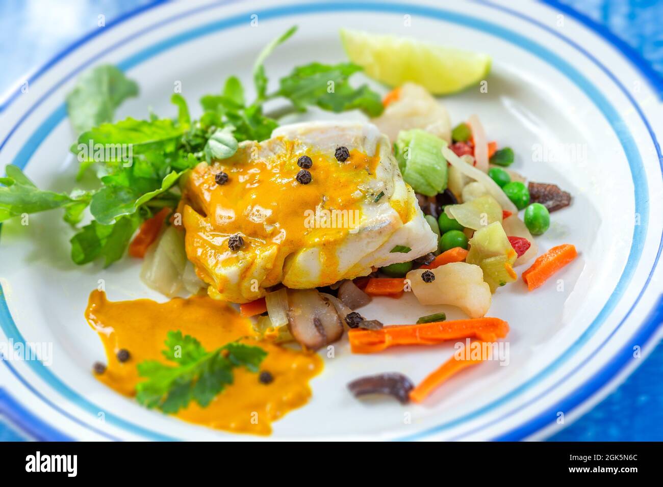 Steamed cod fillet with curry sauce and salad leaves Stock Photo - Alamy