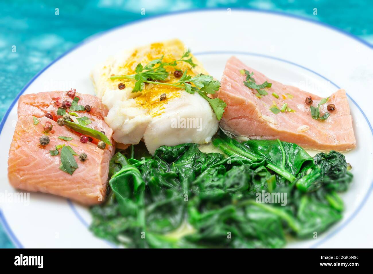 Cod and Salmon fillet with rice and spinach garnish Stock Photo - Alamy