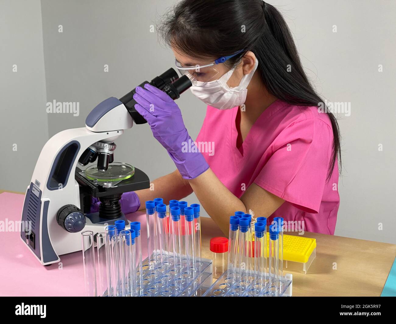 Woman observing through a microscope in a laboratory Stock Photo - Alamy