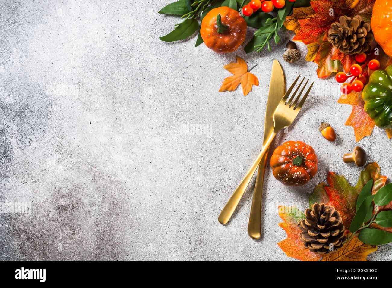 Autumn table setting with white plate, golden cutlery and fall ...