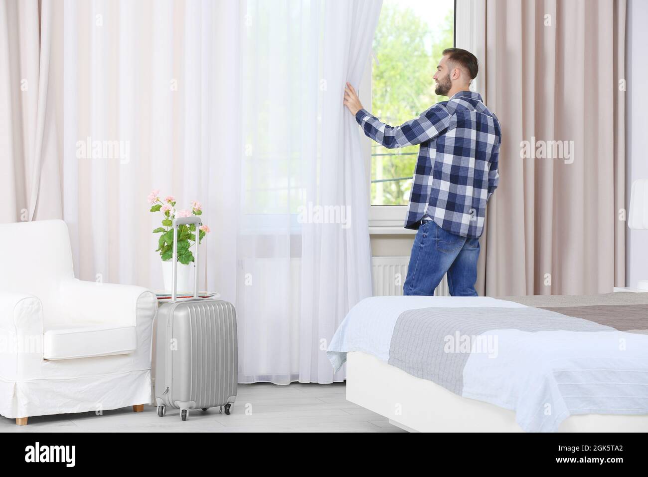 Young man standing near window in hotel room Stock Photo - Alamy