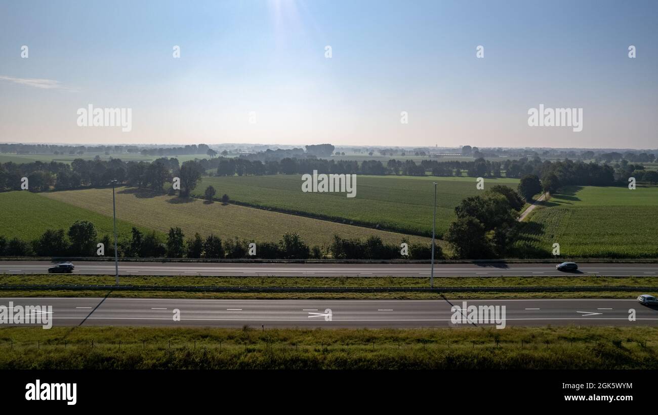 Aerial view of the road between farm fields and plantations under a ...