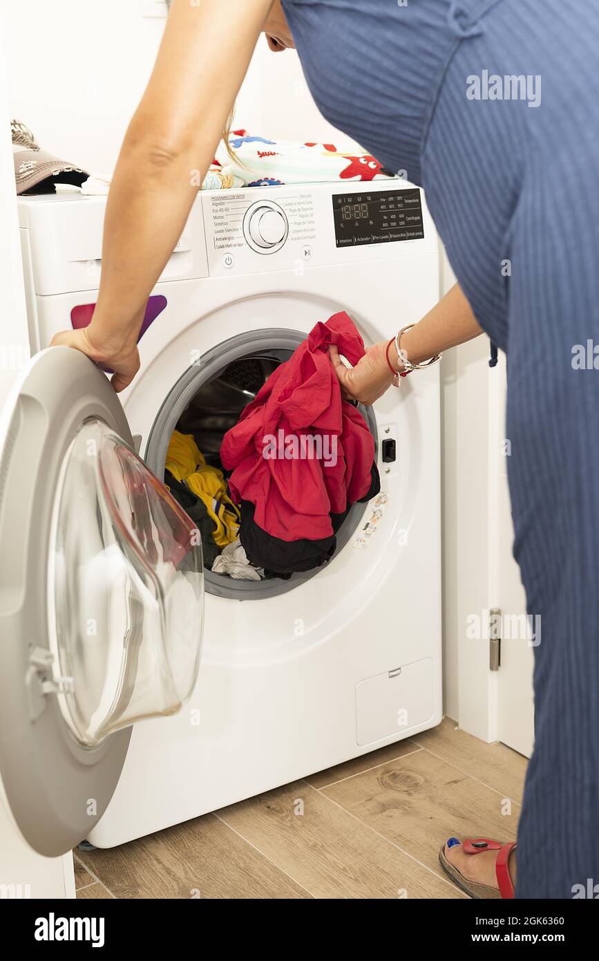Rear view of a woman putting clothes in a washing machine Stock Photo ...