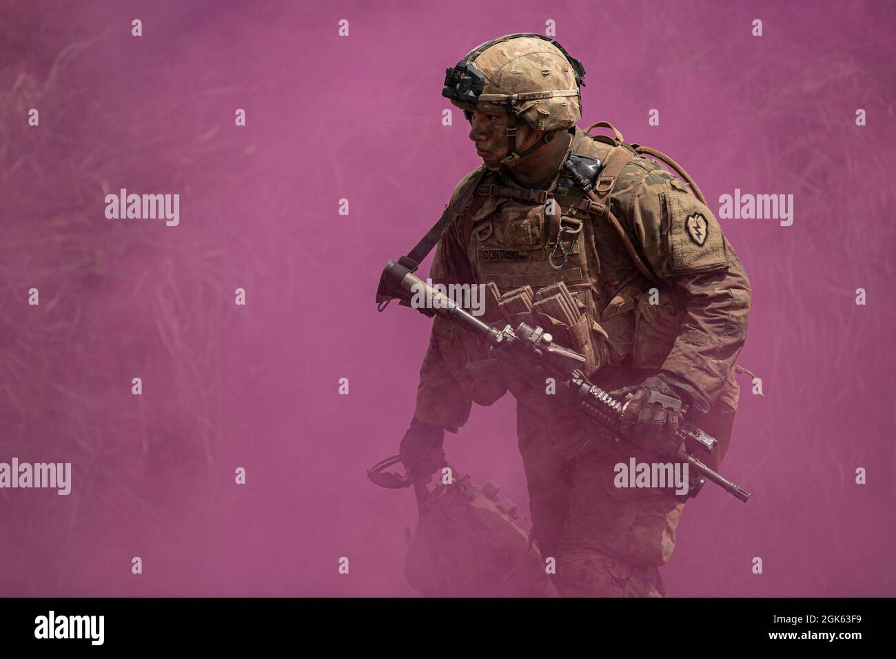 A U.S. Army Solider with Task Force Warrior walks through violet smoke ...