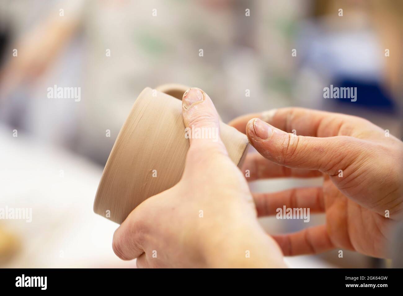 Clay modeling workshop. In hand is a freshly molded earthenware cup ...