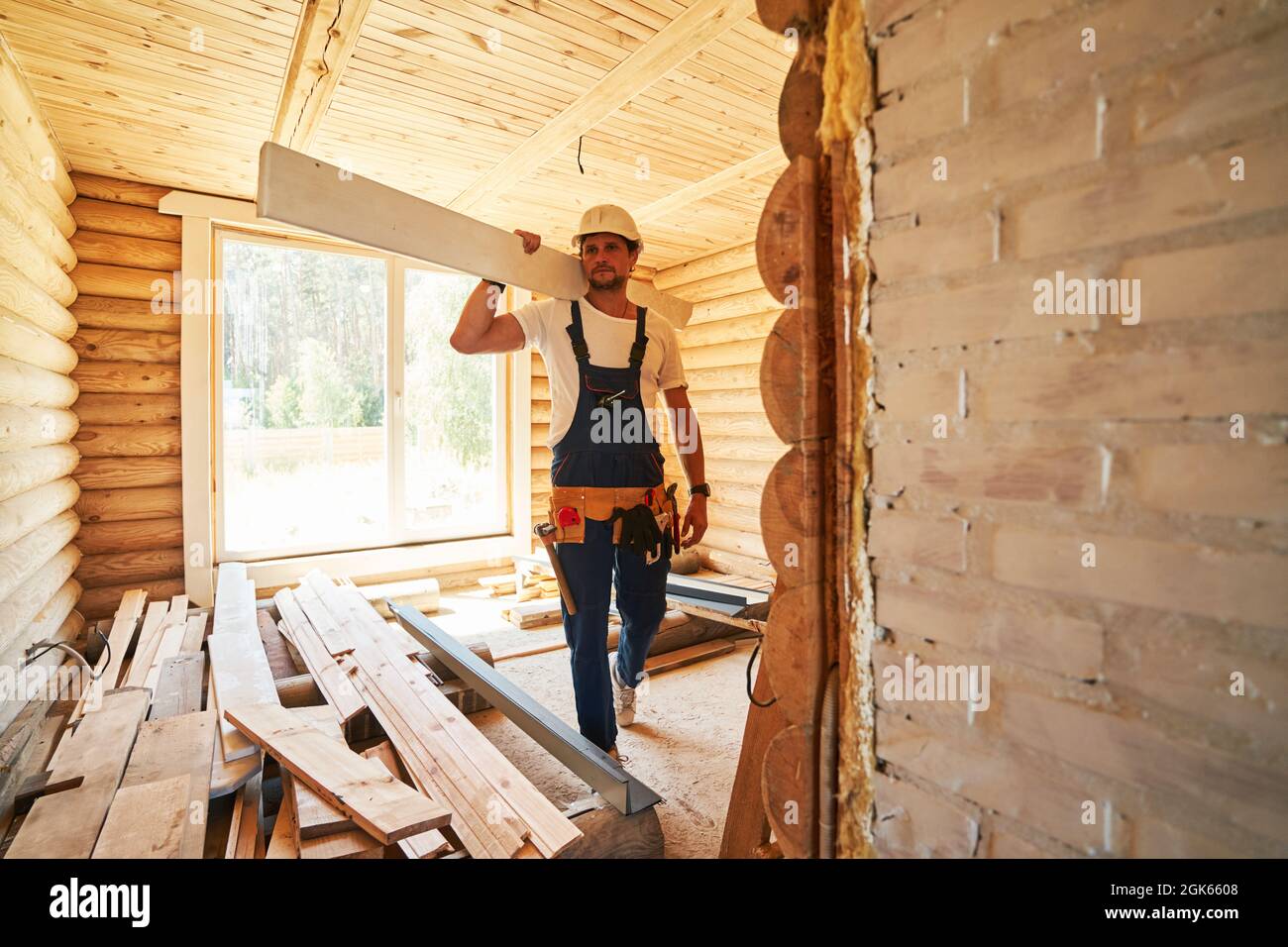 Construction worker carrying a board on his shoulder Stock Photo - Alamy
