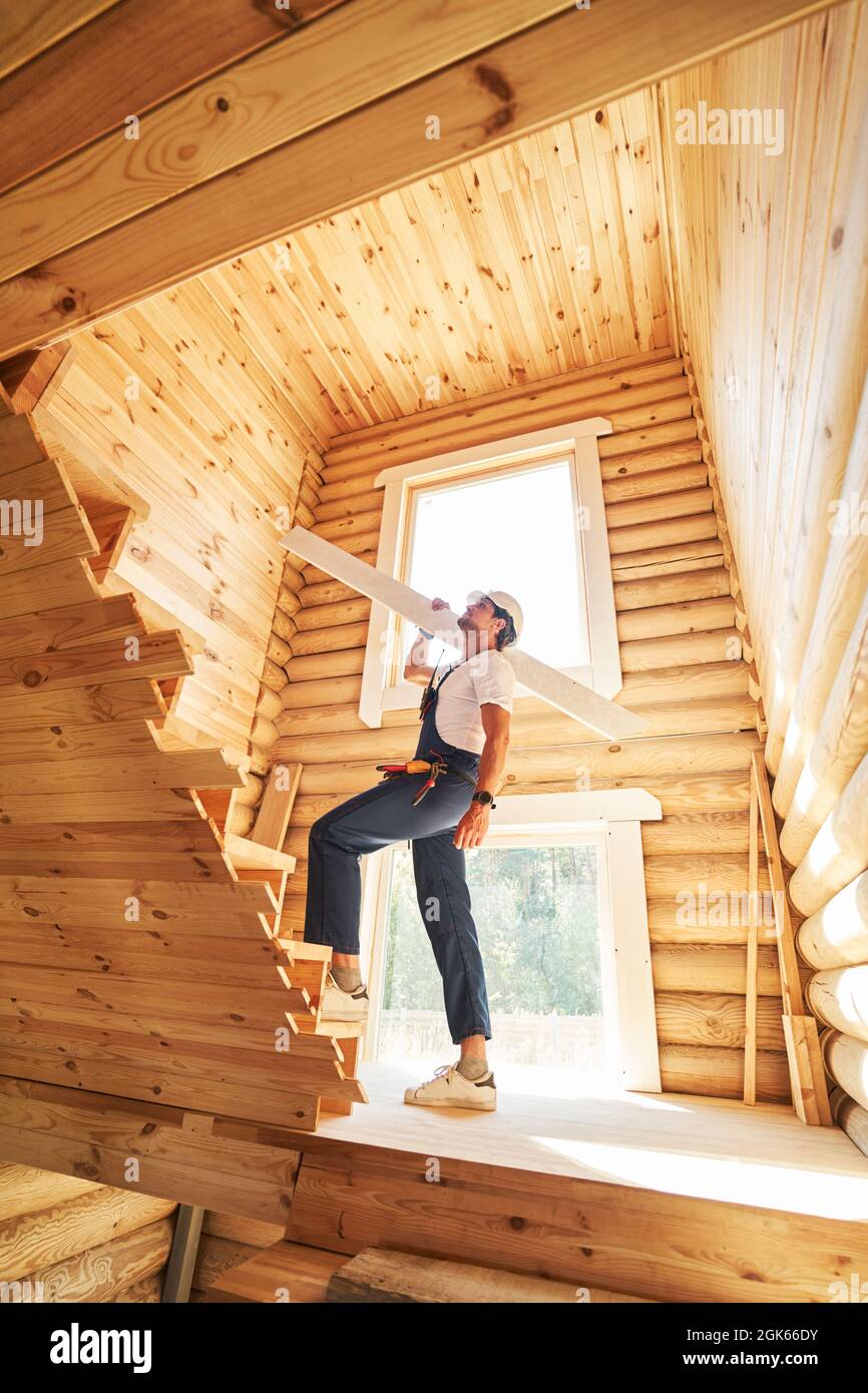 Builder making a step on stairs with board on shoulder Stock Photo - Alamy