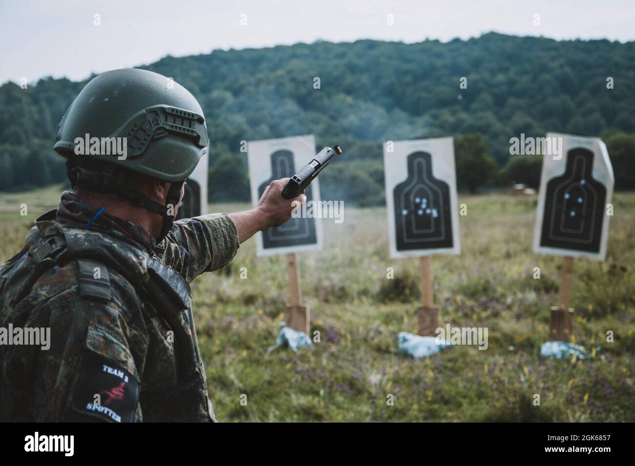 A Bulgarian sniper uses his sidearm to shoot a row of targets during ...