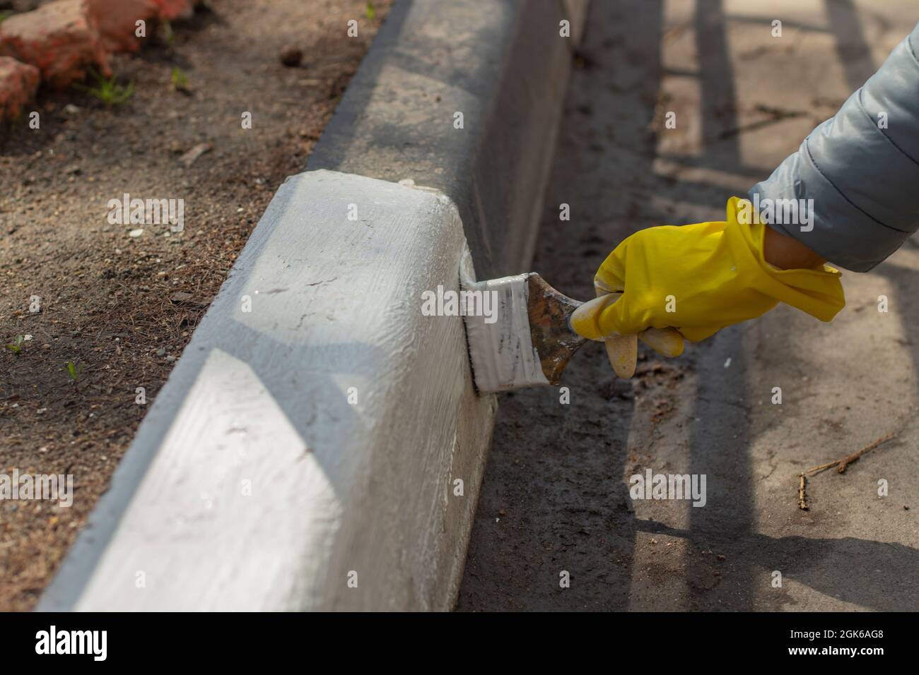 Painting borders with white paint. Applying oil paint to asphalt ...