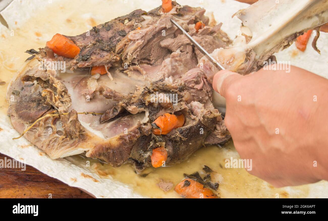 A woman's hand separates the fried meat from the bones, cutting it with ...