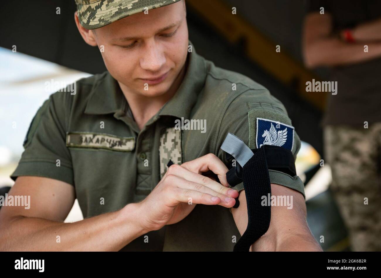 A Ukrainian Air Force Airman demonstrates how to apply a tourniquet ...