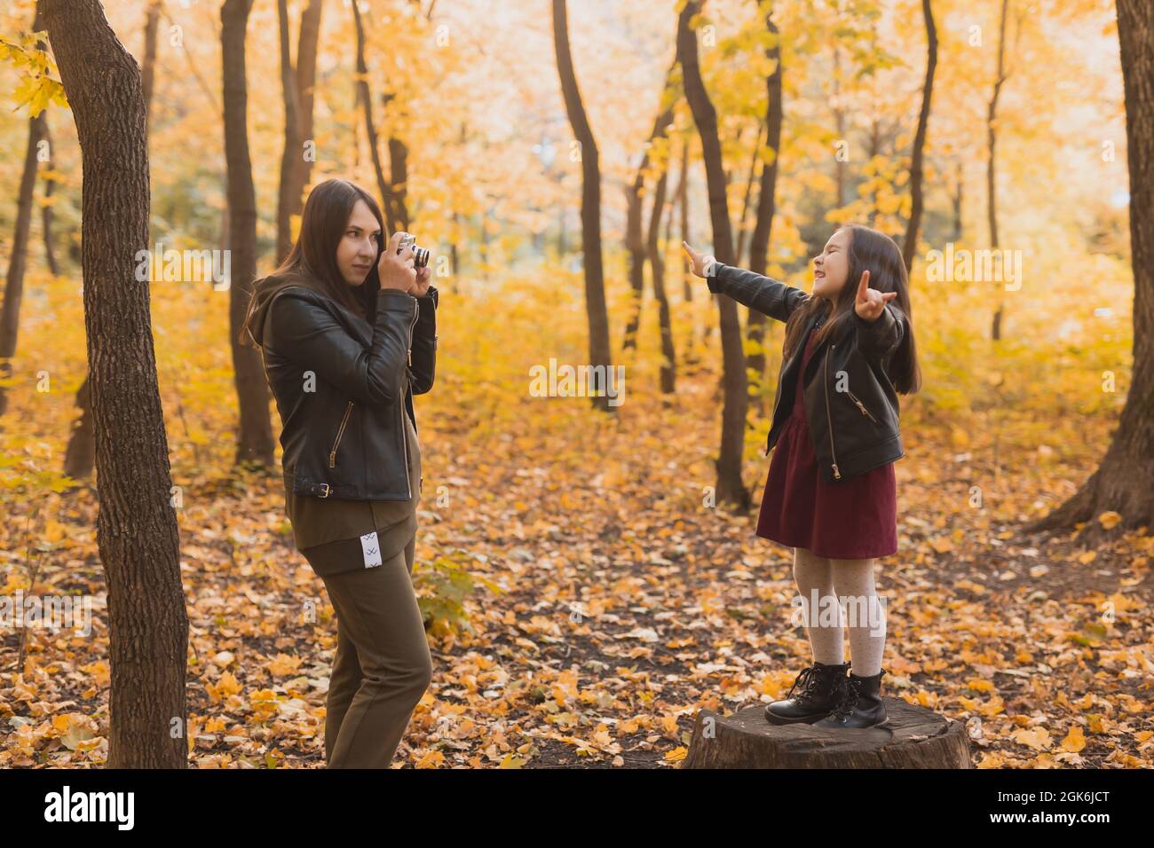 Mother photographer takes pictures of a her daughter in the park in ...