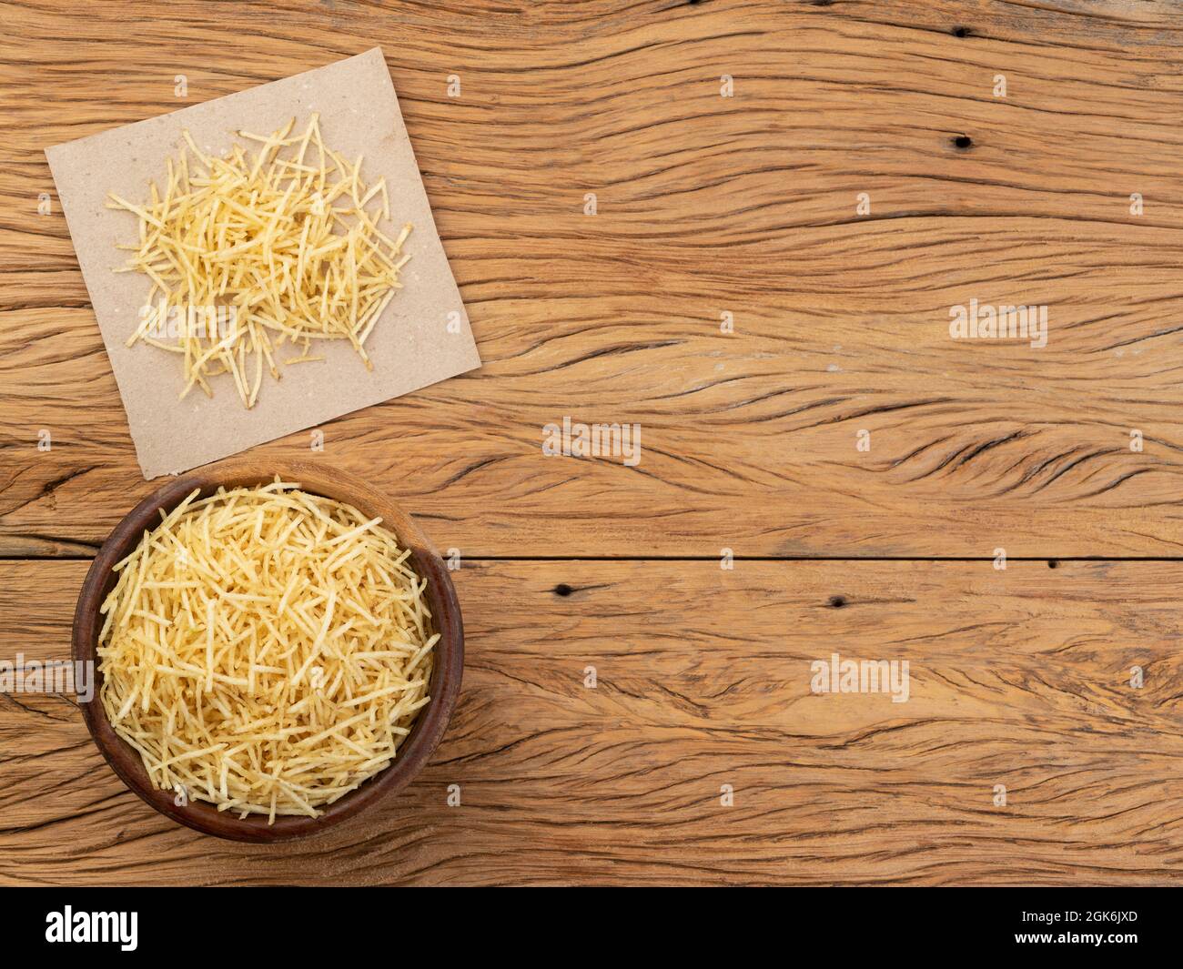 Potato straw or shoestring potato in a bowl over wooden table with copy ...