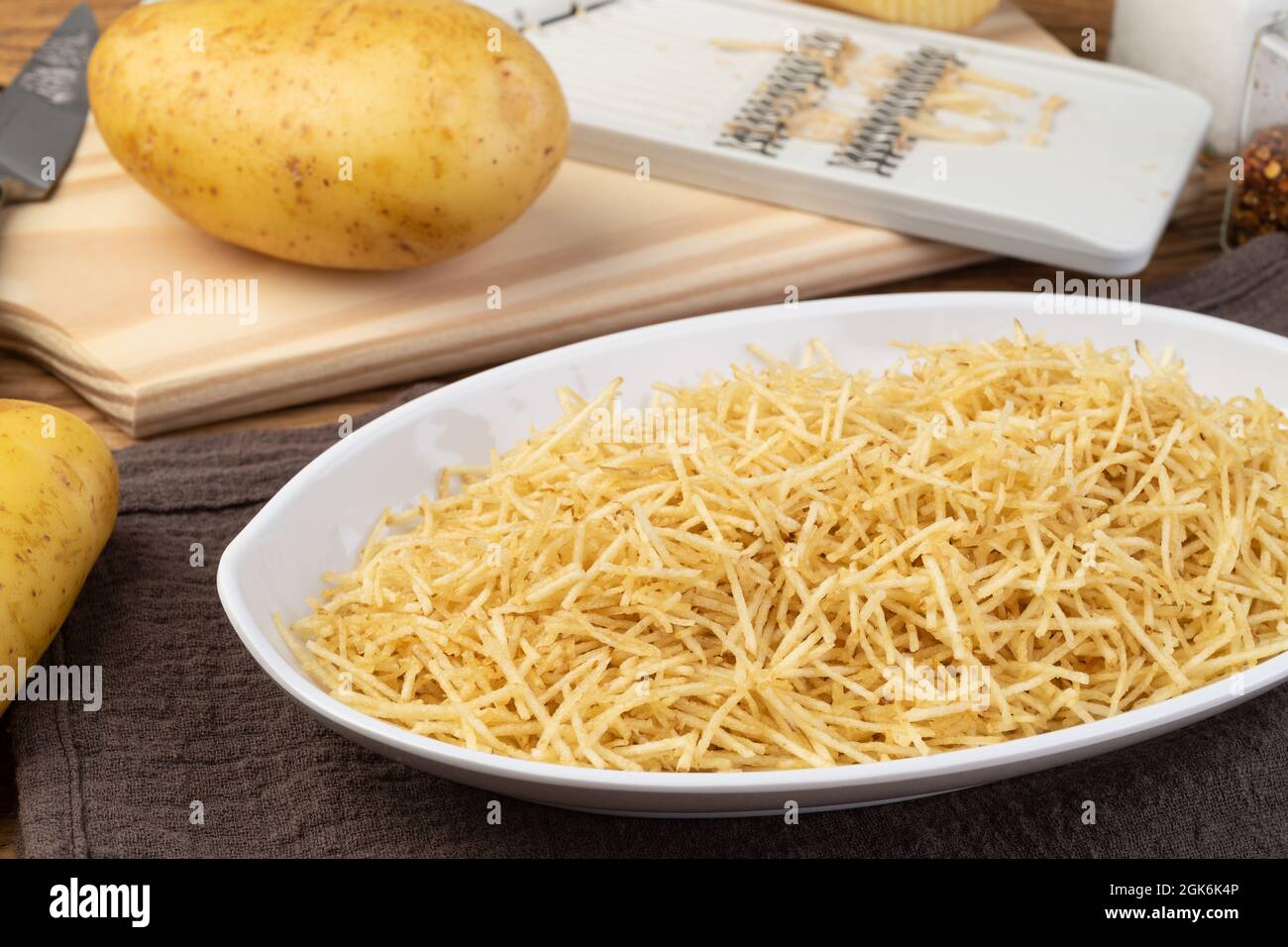 Potato straw or shoestring potato in a white plate with raw potatoes ...