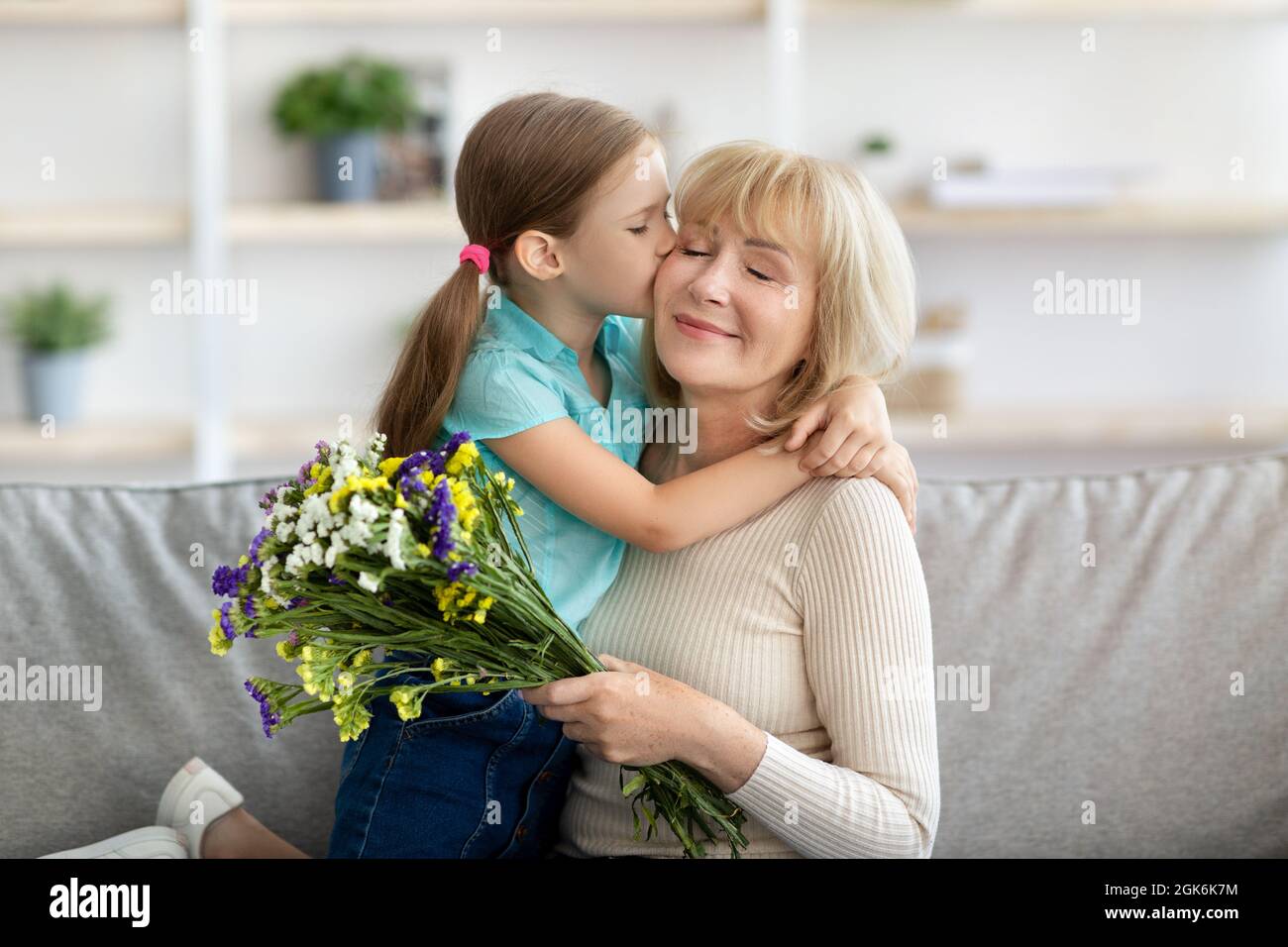 Little girl kissing and greeting woman with flowers Stock Photo - Alamy