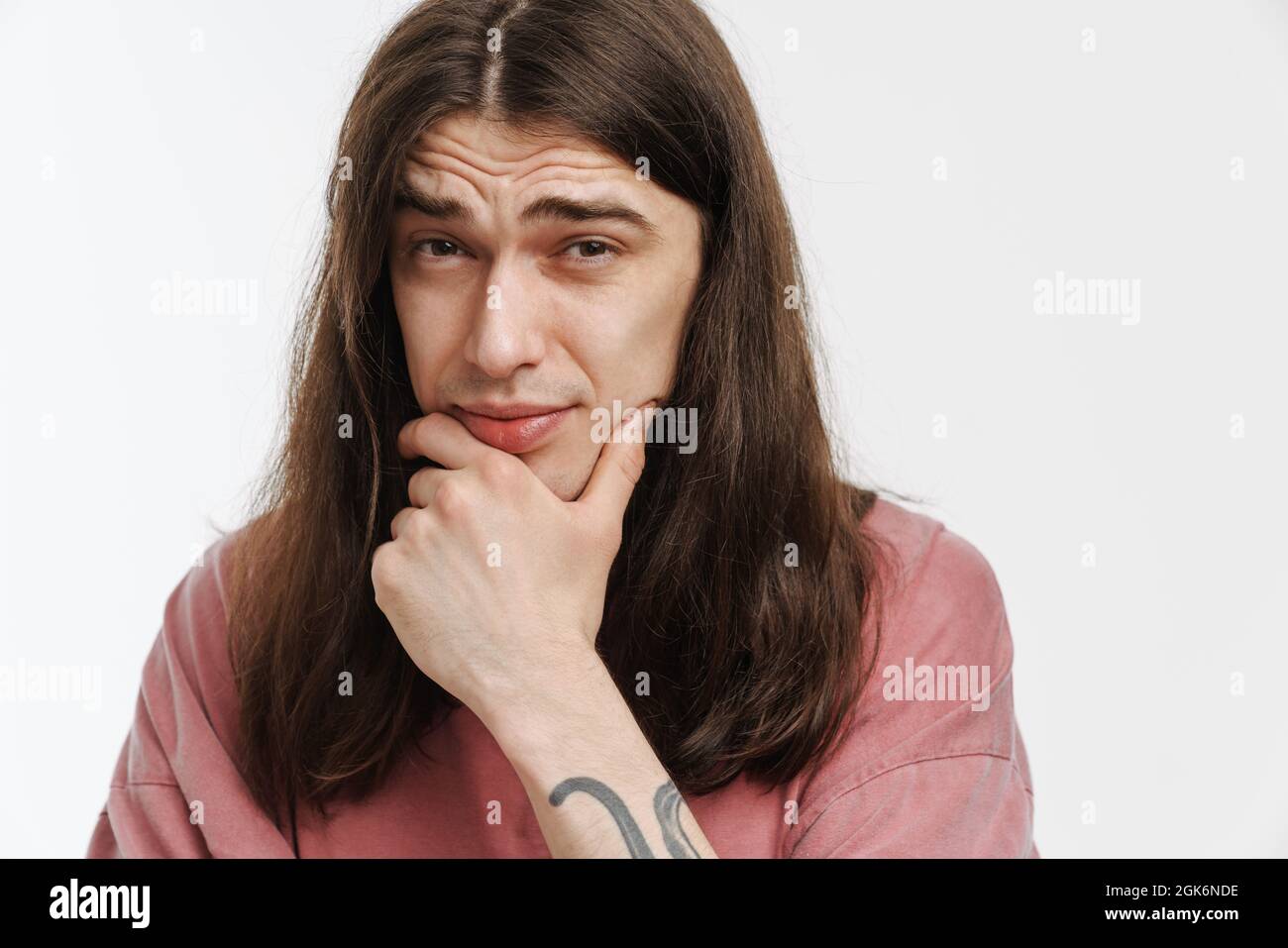 Young confused man with long hair posing and looking at camera isolated ...