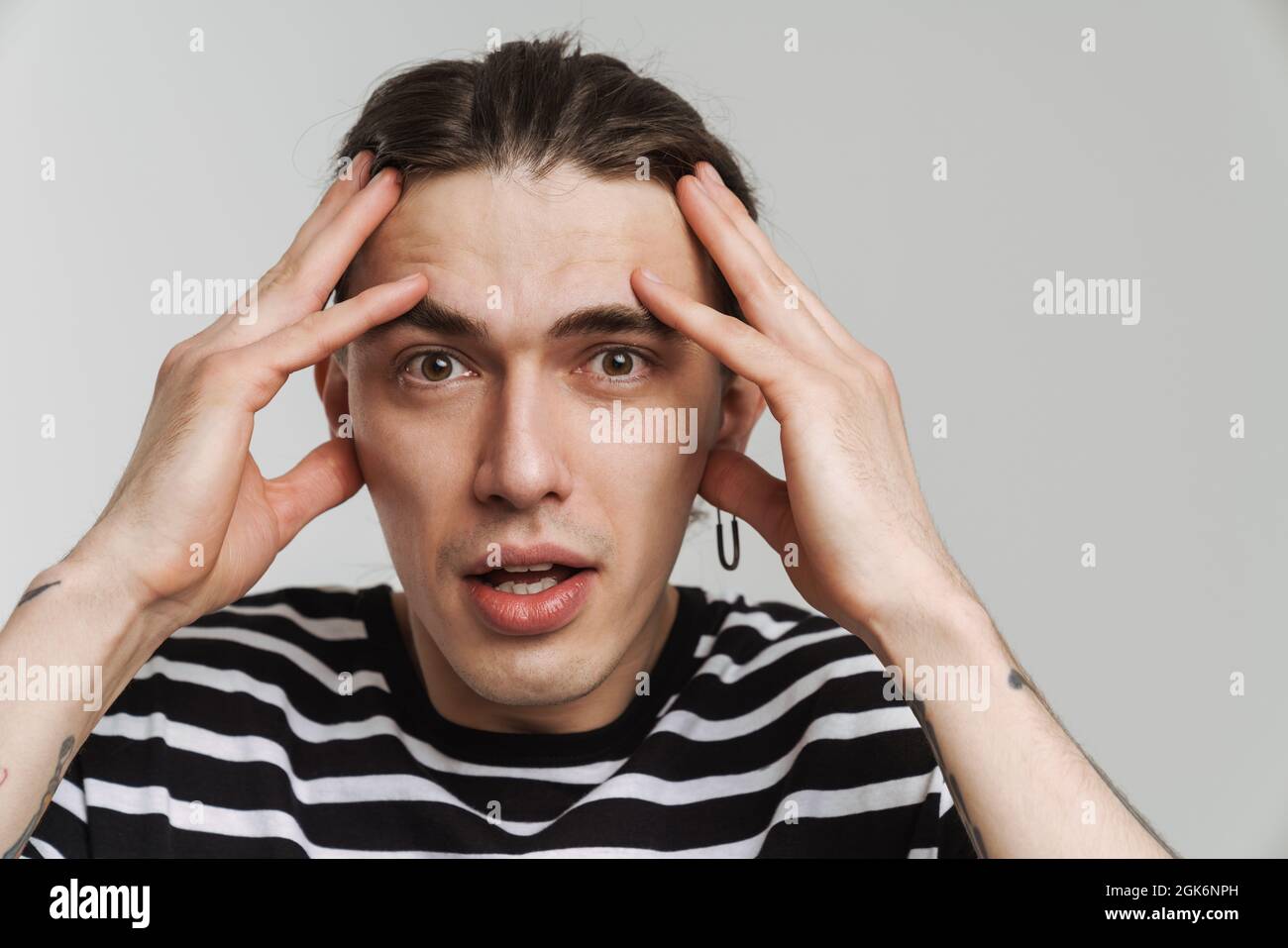 Young white man with earring expressing surprise at camera isolated ...