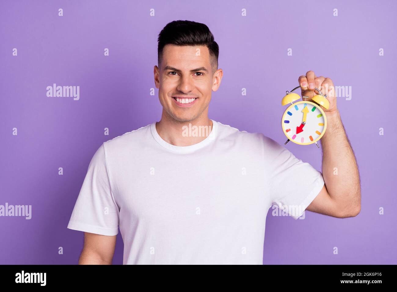 Photo of young man happy positive smile show clock alarm time ...