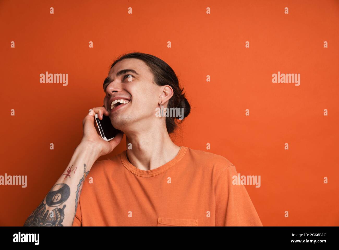 Young white man with tattoo laughing while talking on cellphone ...