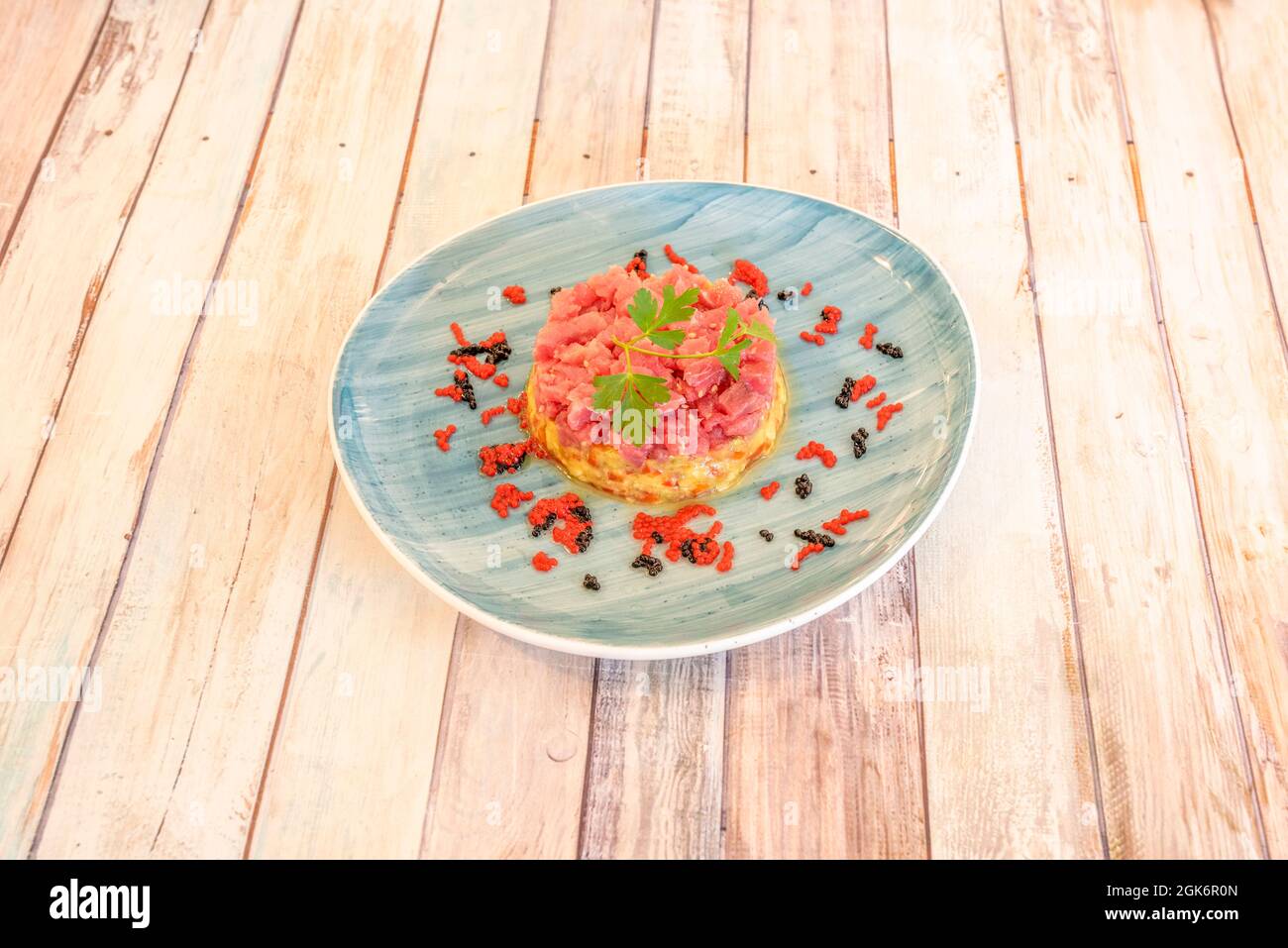 Red tuna tartare with red and black fish roe served on a blue plate ...