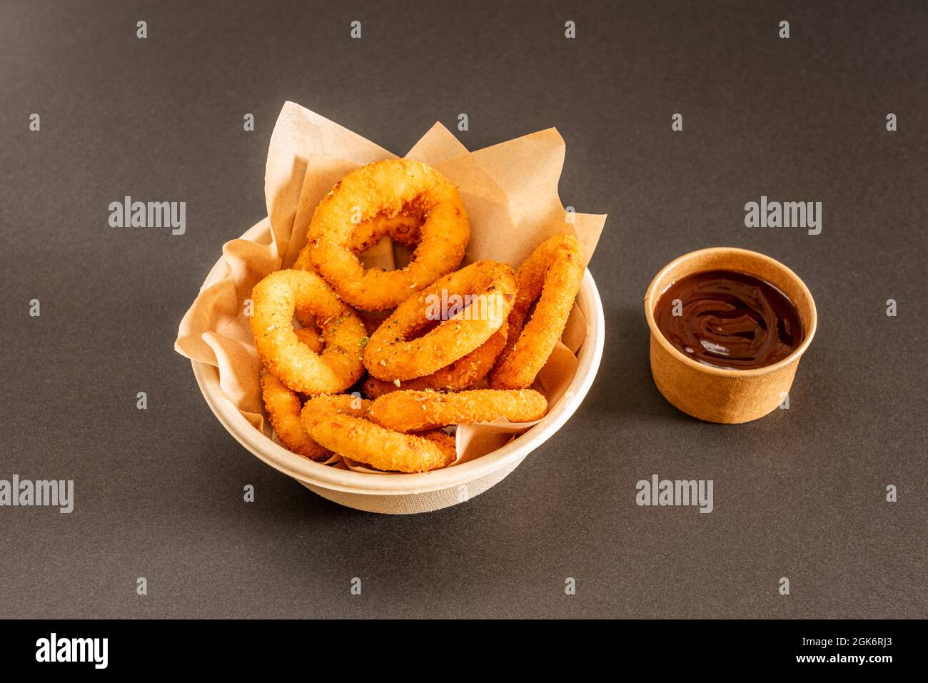 portion of onion rings breaded with barbecue sauce to dip in a ...