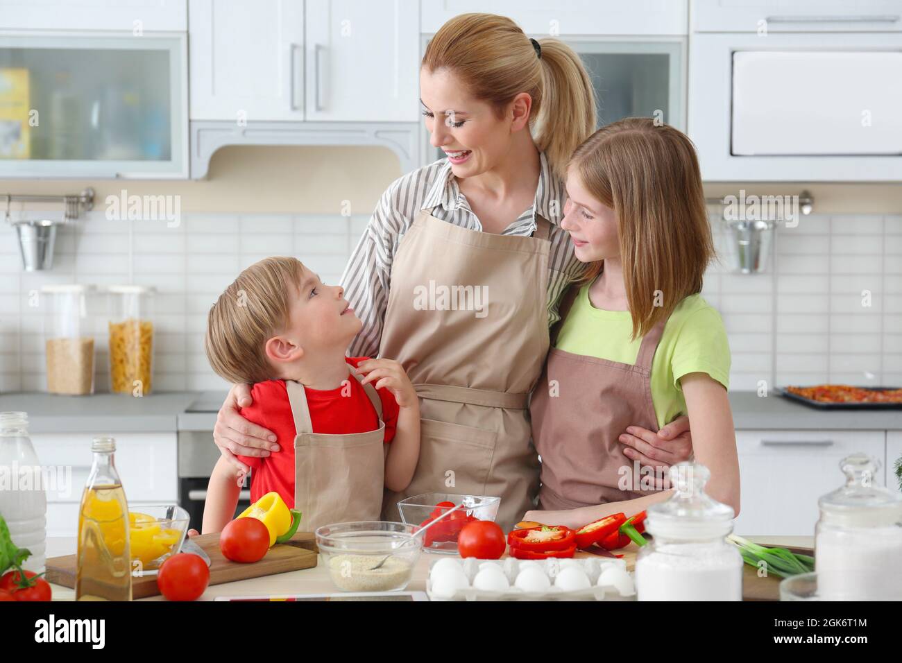 Mother and children making meal together in kitchen. Cooking classes ...